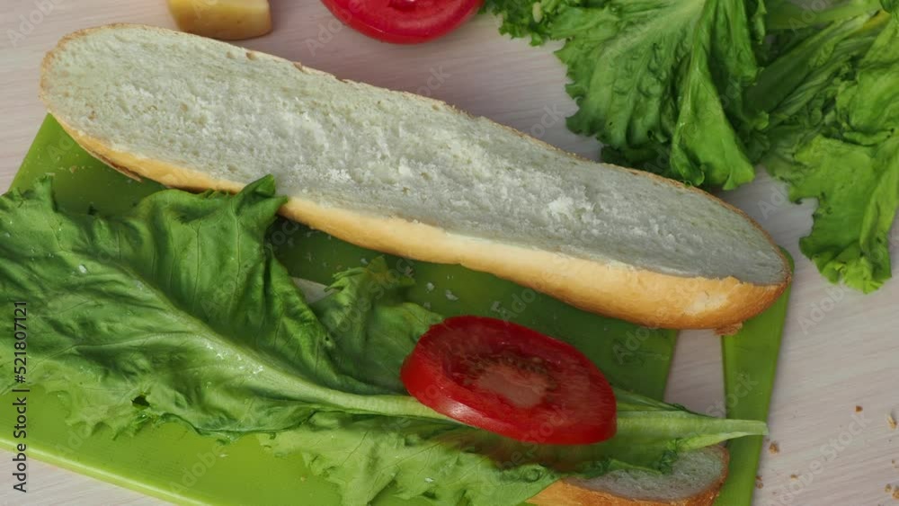 a girl makes a sandwich for a snack or for lunch at work. cuts a tomato ...