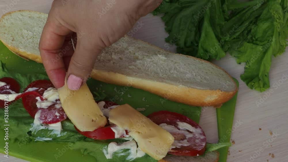 a girl makes a sandwich for a snack or for lunch at work. cuts a tomato ...
