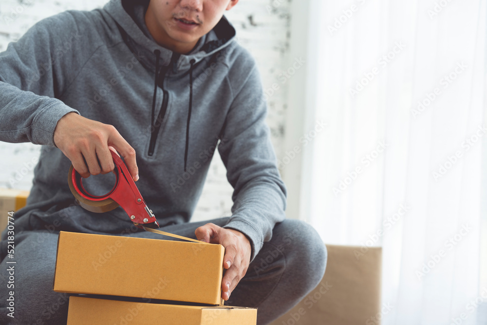 Detail of packing cardboard boxes while moving house. Young man packing ...