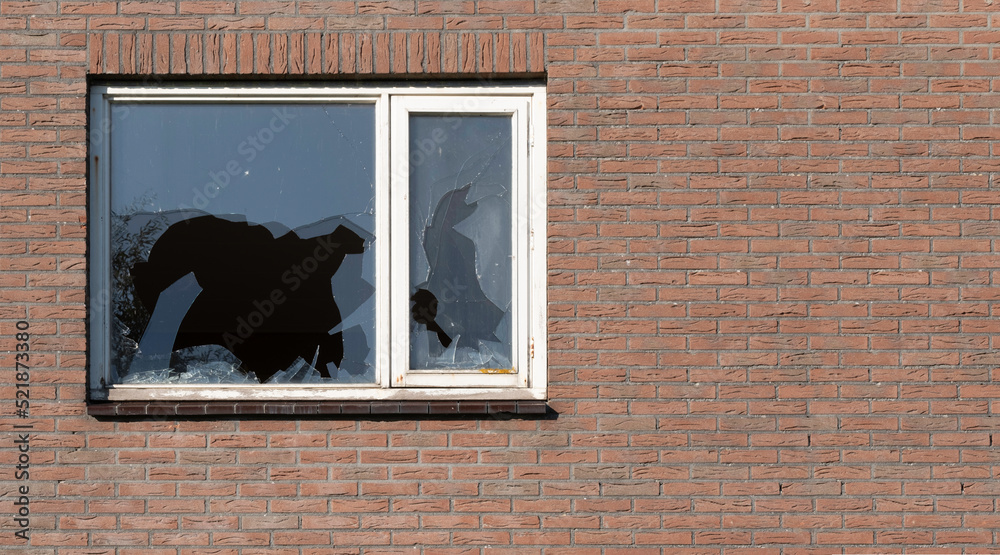 Broken glass window, probably due to vandalism, in a brick wall Stock ...