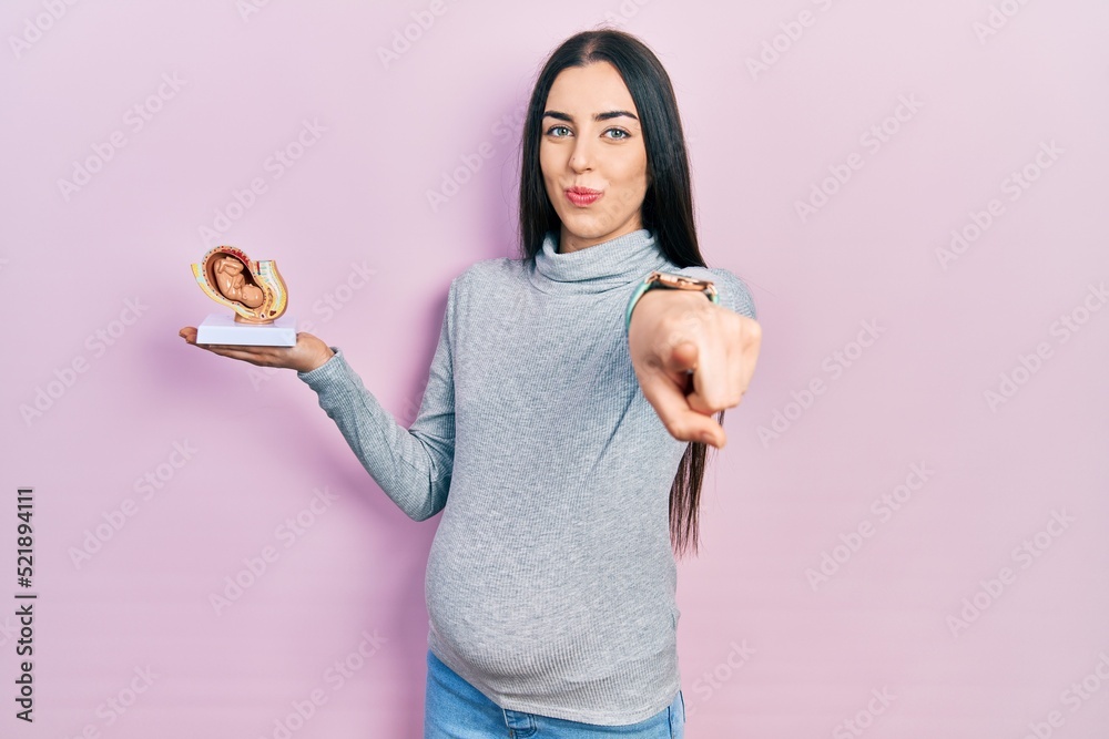 Beautiful woman with blue eyes expecting a baby, holding anatomic fetus ...
