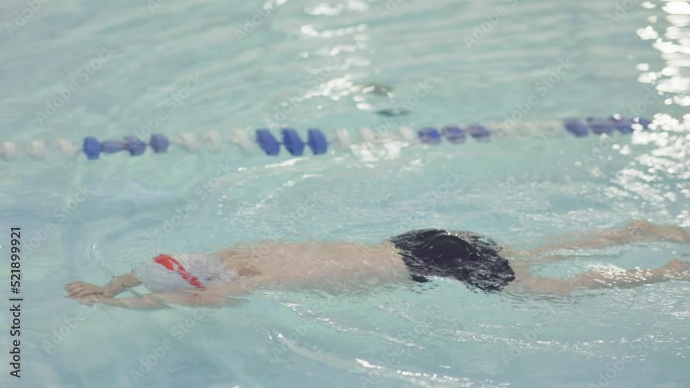 baby swimmer learning to swim using only legs in blue transparent ...