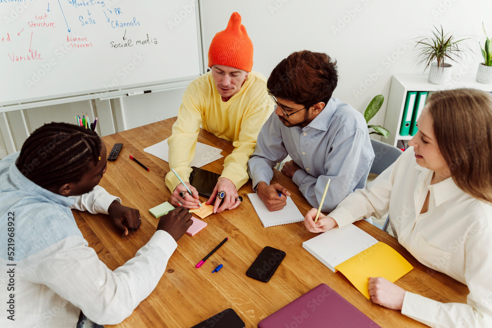 Businessman showing adhesive note to colleagues at desk in office Stock ...