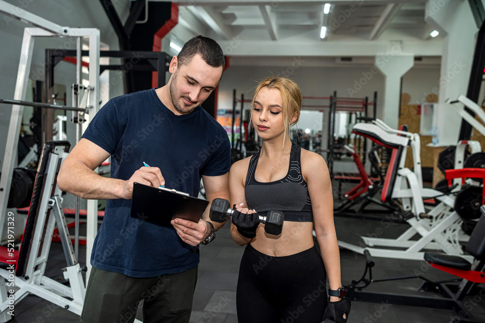 personal trainer with slim woman client doing bicep curls working out ...