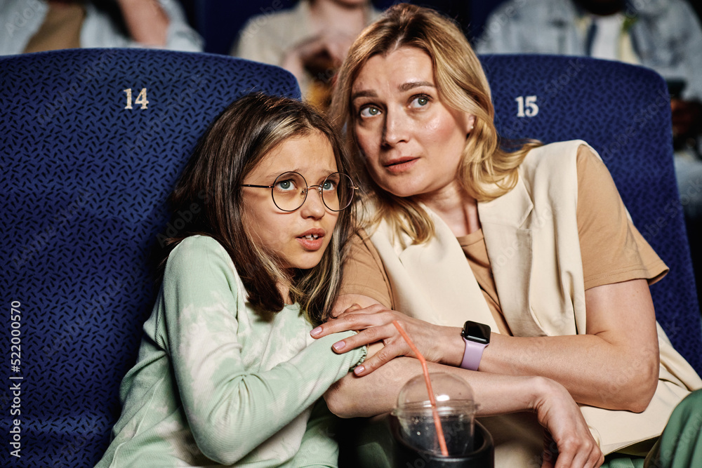 Caucasian woman and her preteen daughter feeling scared when watching ...