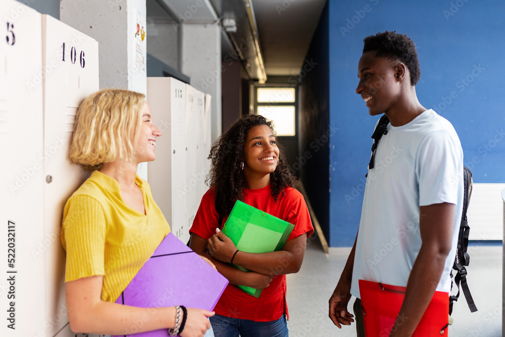 Multiracial group of student friends talking at high school corridor ...