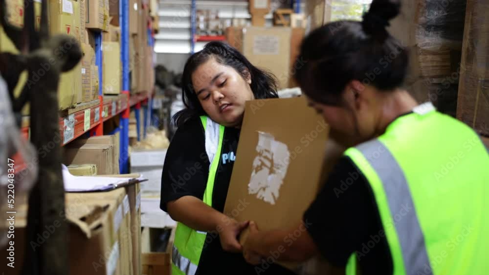Two women worker carrying and lifting heavy cardboard box. Asian obese ...