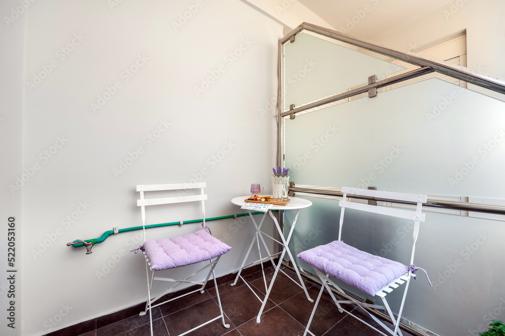 Balcony relax corner with two chaired covered with violet pillows and ...