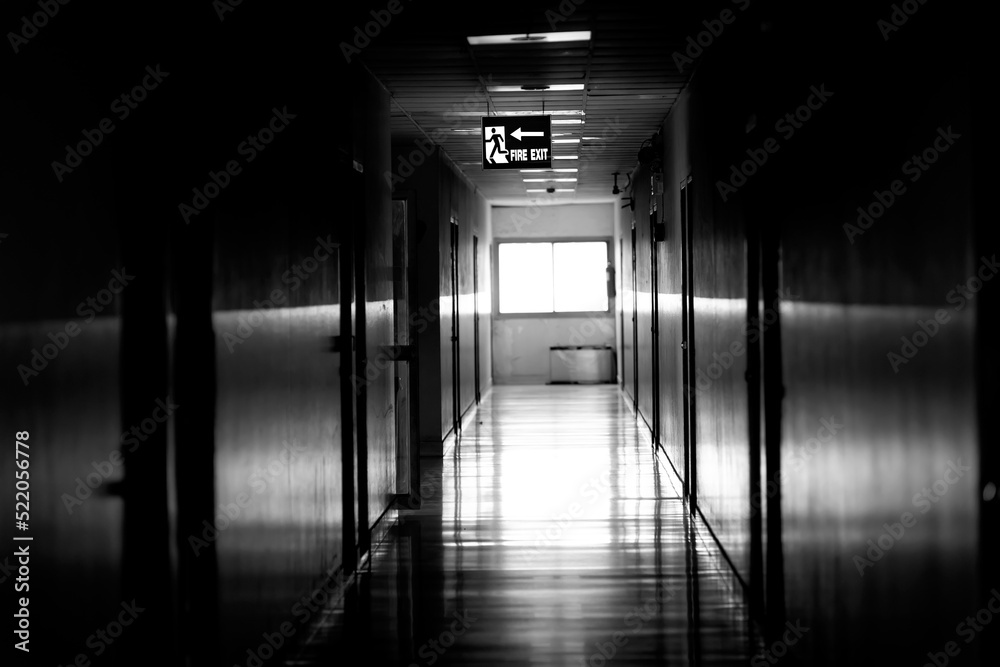 Dramatic black and white of fire exit sign on the corridor of the ...