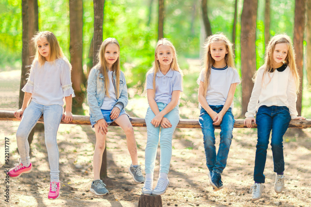 A group of five girls kids on a walk in the summer forest sat down to ...