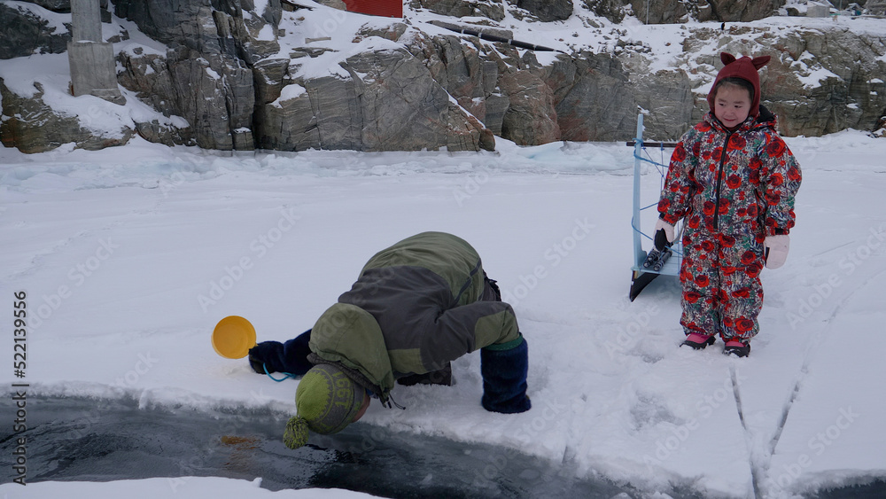 Greenlandic Inuit father checks sea ice thickness with his young girl ...