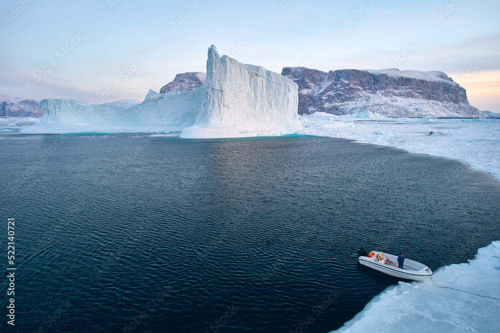 Indigenous inuit hunter waits for prey, boat anchored to sea ice floe ...