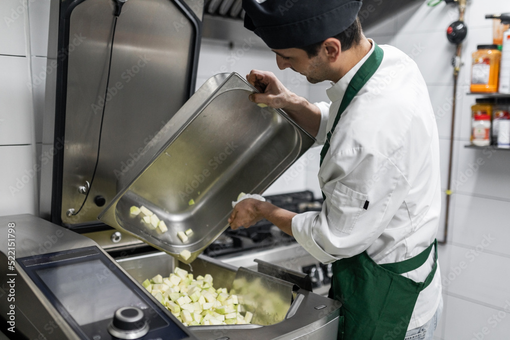 chef cooking vegetables in the industrial fryer in a kitchen Stock ...