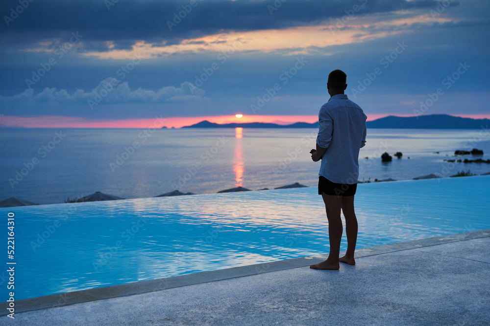 Man watching the sunrise by the pool at the seashore Stock Photo ...