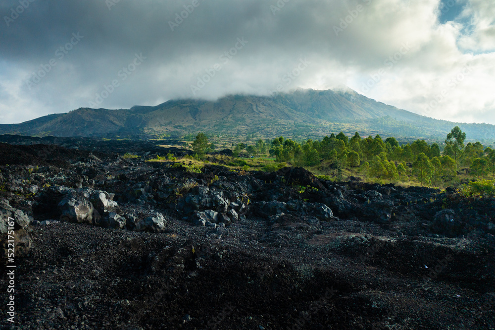 Texture of volcano lava rocks and Mount Batur in background Stock Photo ...