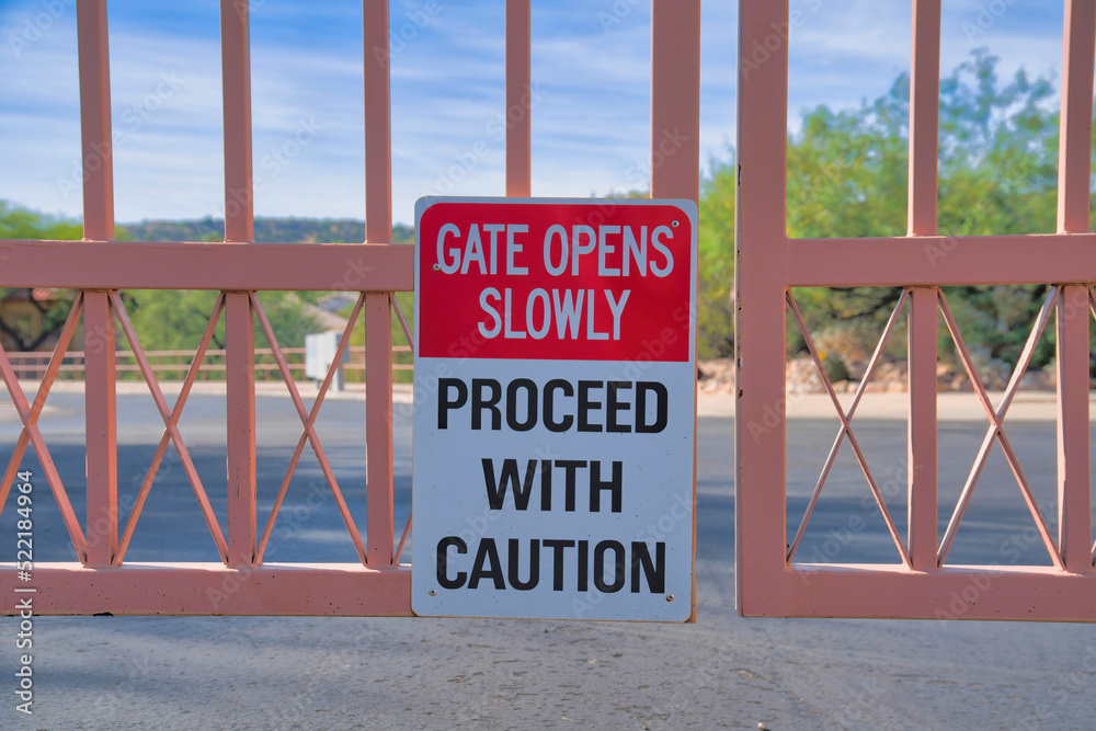 Gate opens slowly Proceed with caution signage on a metal gate at ...