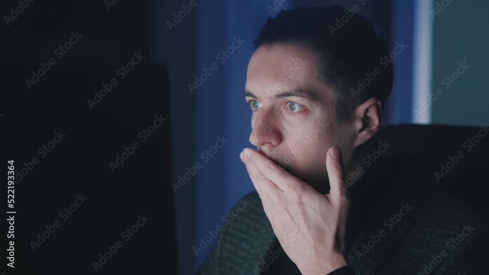 Afraid and shocked man looking at monitor screen, takes off glasses and ...