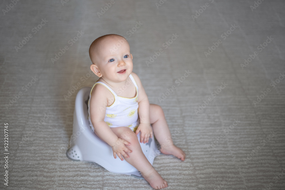 Cute baby in a diaper sitting on a potty. Toilet and potty training. A ...