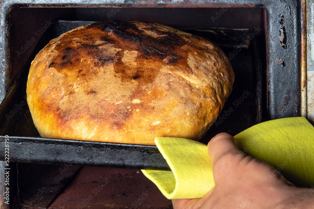 Foto de Baking Ukrainian bread at home. The baker takes out a tray with ...