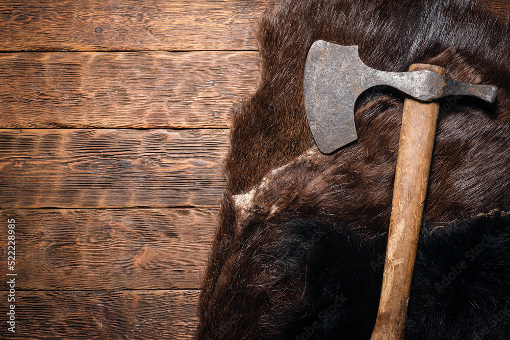 Viking axe and beast fur skin on the brown wooden table flat lay ...