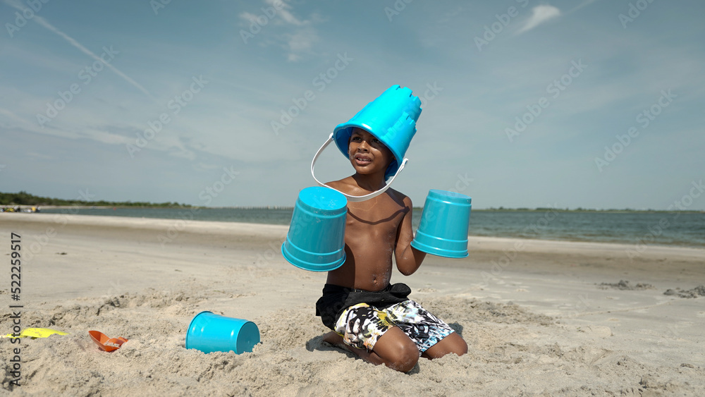 Boy (6-7) wearing buckets on head and hands on beach Stock Photo ...