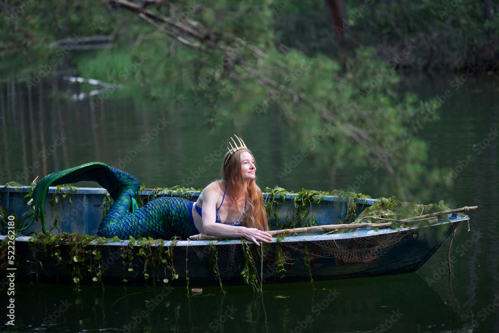 Mermaid story. The little mermaid sits in a boat. Mermaid at sunset ...