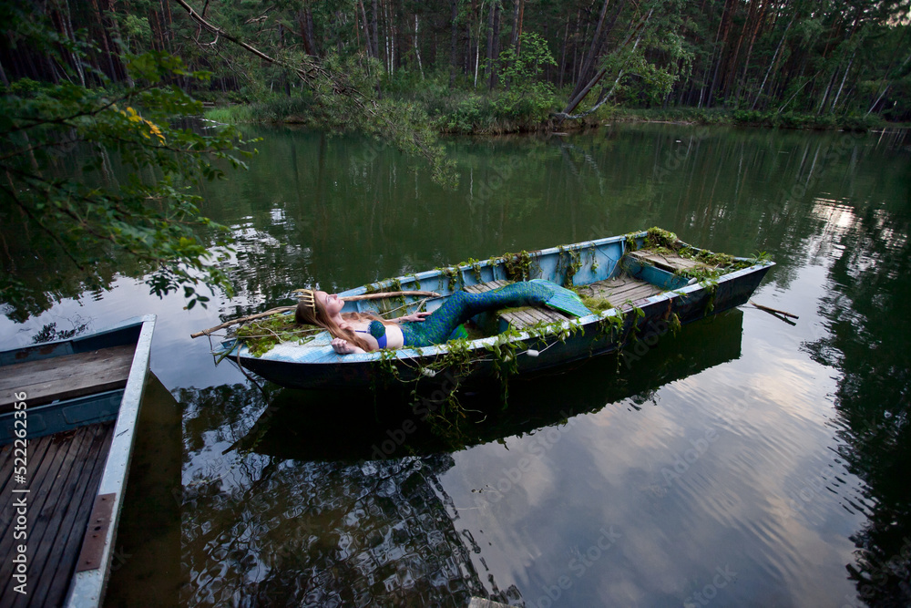 Mermaid story. The little mermaid sits in a boat. Mermaid at sunset ...