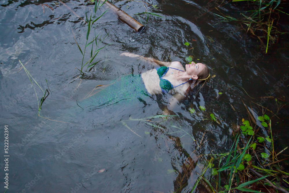 Mermaid story. The little mermaid sits in a boat. Mermaid at sunset ...