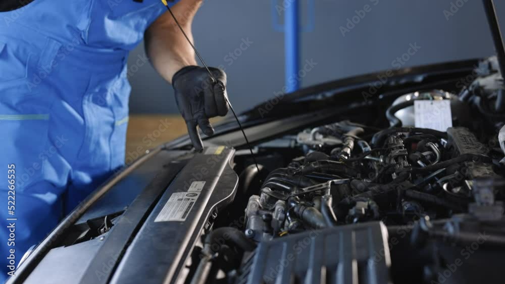 Close-up of automotive mechanic checks the oil level on the car engine ...