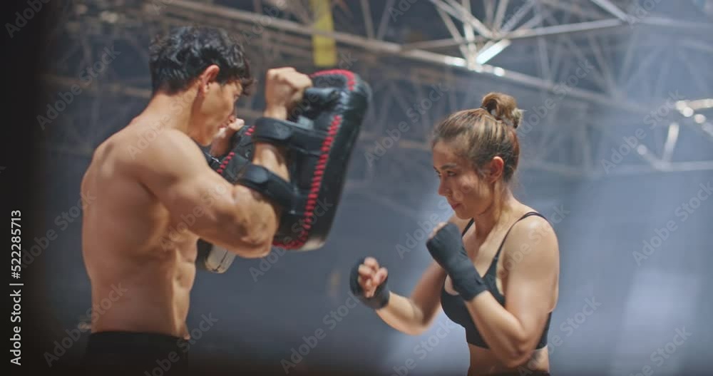 Professional female boxer doing boxing workout punching her instructor ...