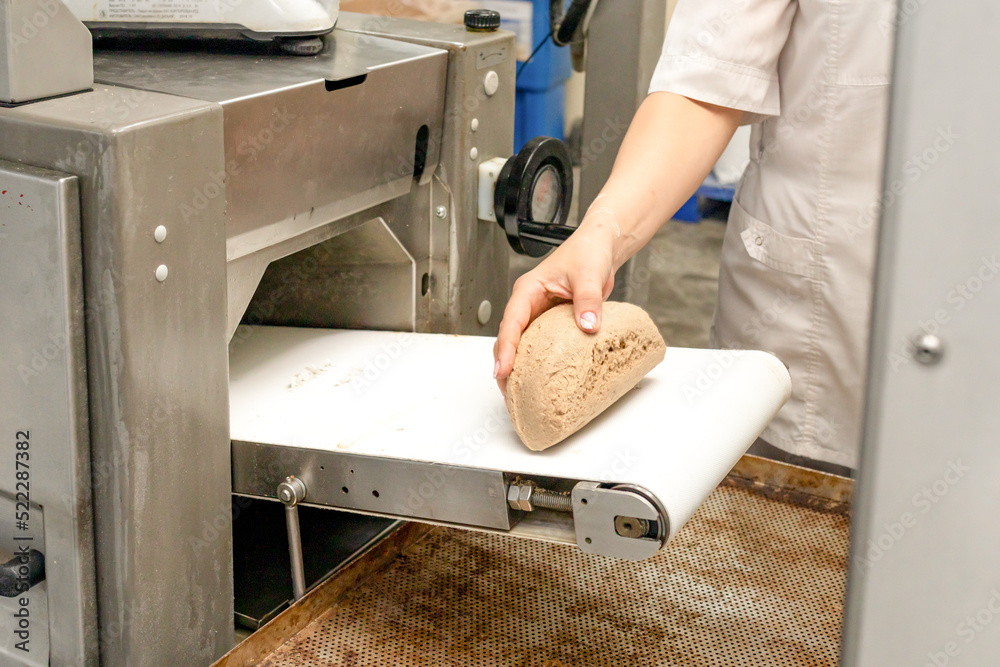Fotografia do Stock: Molded dough on conveyor belt. Operator's hand ...