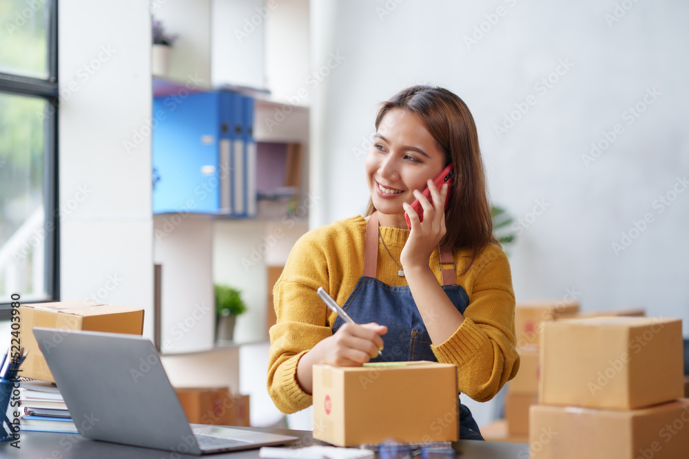 Foto de Online business owner Asian woman answering the phone talking ...