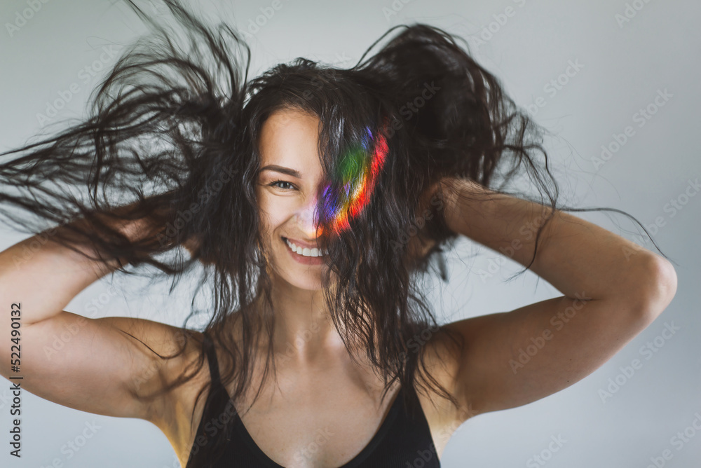 Closeup portrait of brunette girl shaking hair with ray of rainbow ...