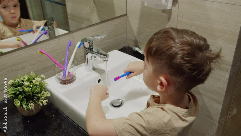 Portrait happy cute young child brushing teeth in bathroom and smiling ...