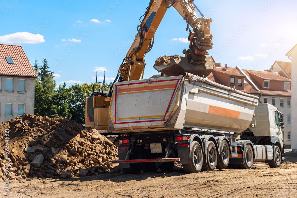 Heavy excavatore machine uploading waste and debris rubble into dump ...