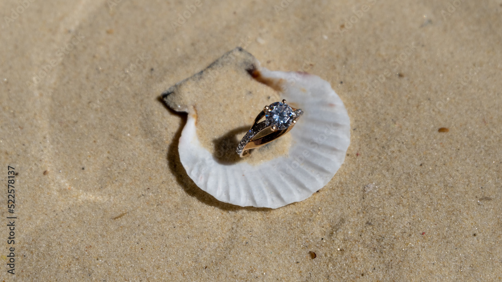 engagement gold ring with a large diamond in a shell on the golden sea ...