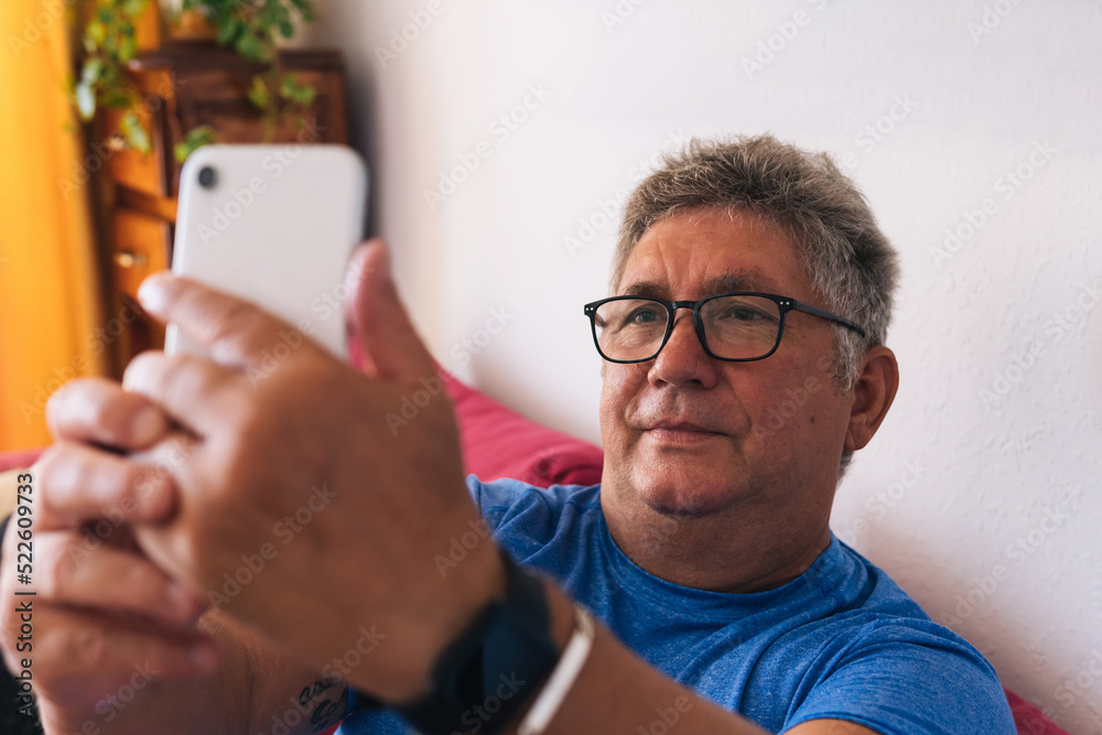 Older man with gray hair using mobile phone in his living room. Elderly ...