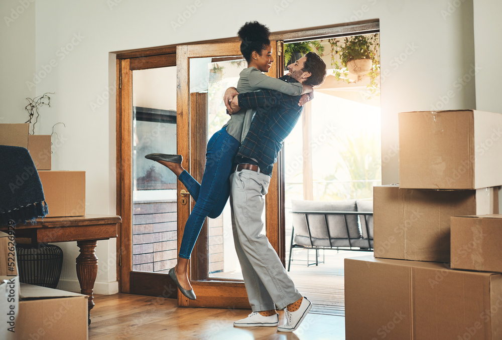 Joyful interracial couple moving in to a new home together hugging ...