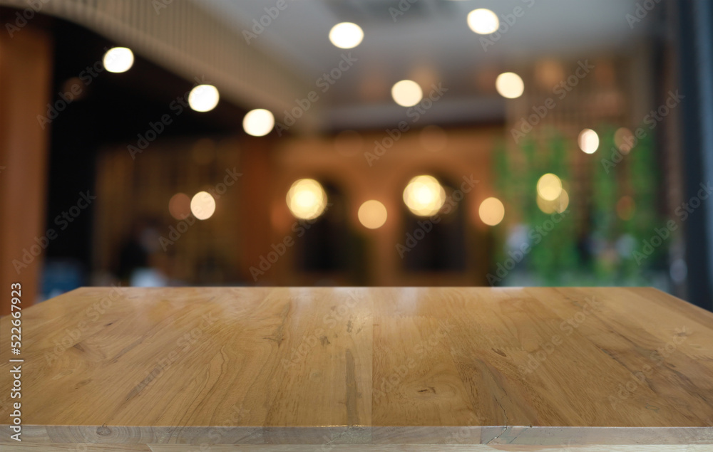 Empty wooden table in front of abstract blurred background of coffee ...