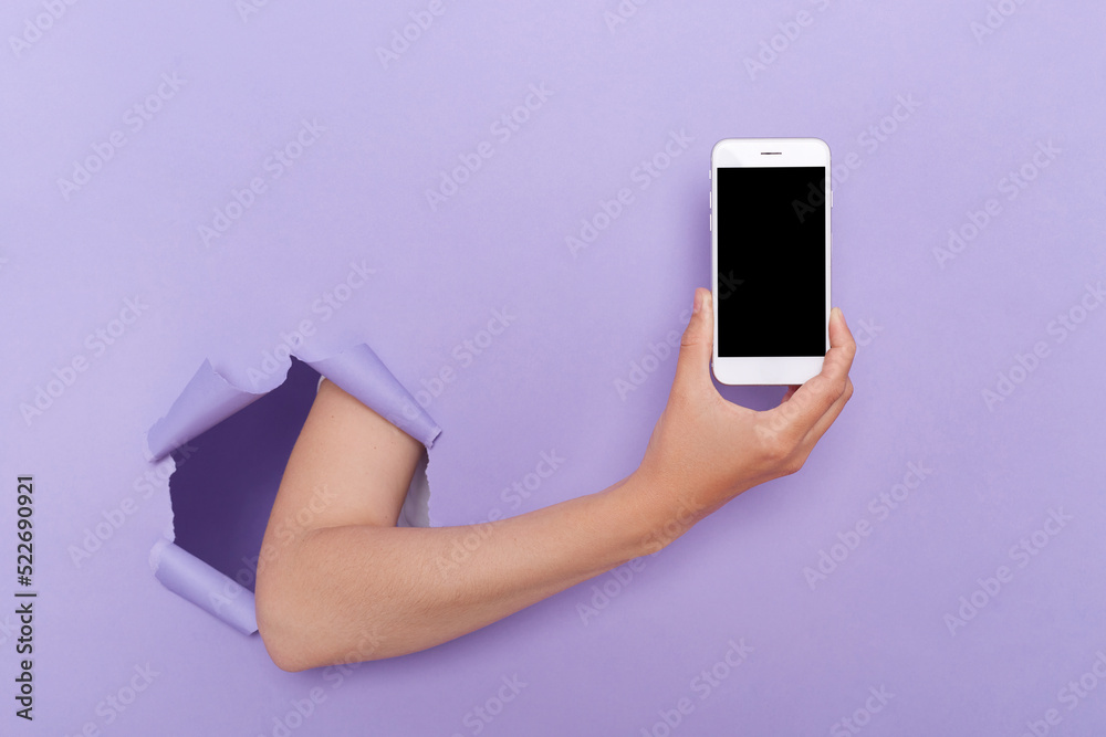 Indoor shot of person's hand holding phone from purple torn paper ...