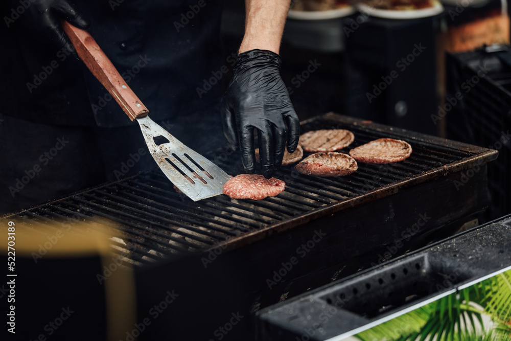 Chef making burger meat at the open air restaurant grill. Festival food ...