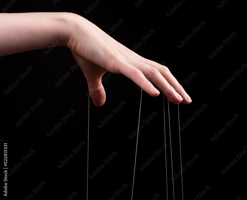 Manipulation, abuse concept. Female hand pulling strings on black ...