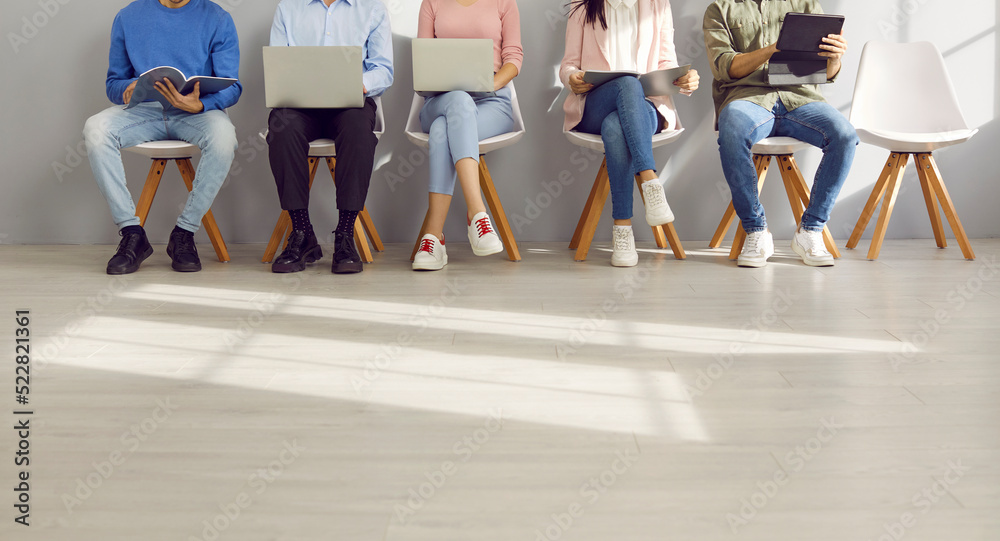 Group of people sitting in line and using computers. Five men and women ...