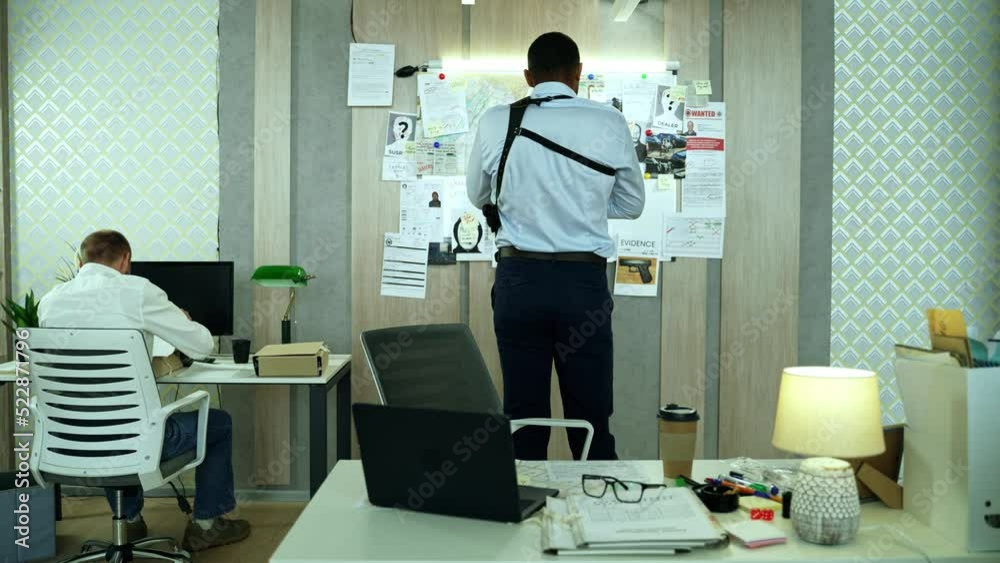 Back view of detective thinking in front of investigation board while ...