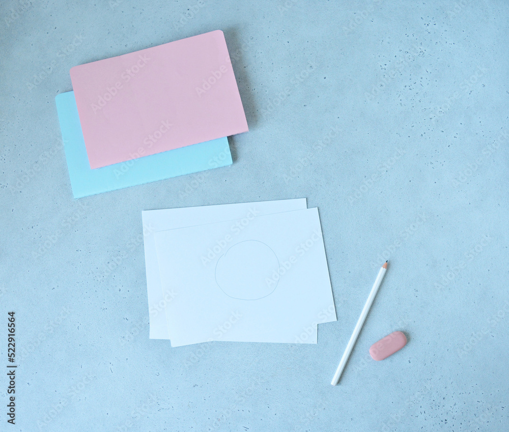 Paper sheets with drawn circle, notebooks, white pencil, and pink ...