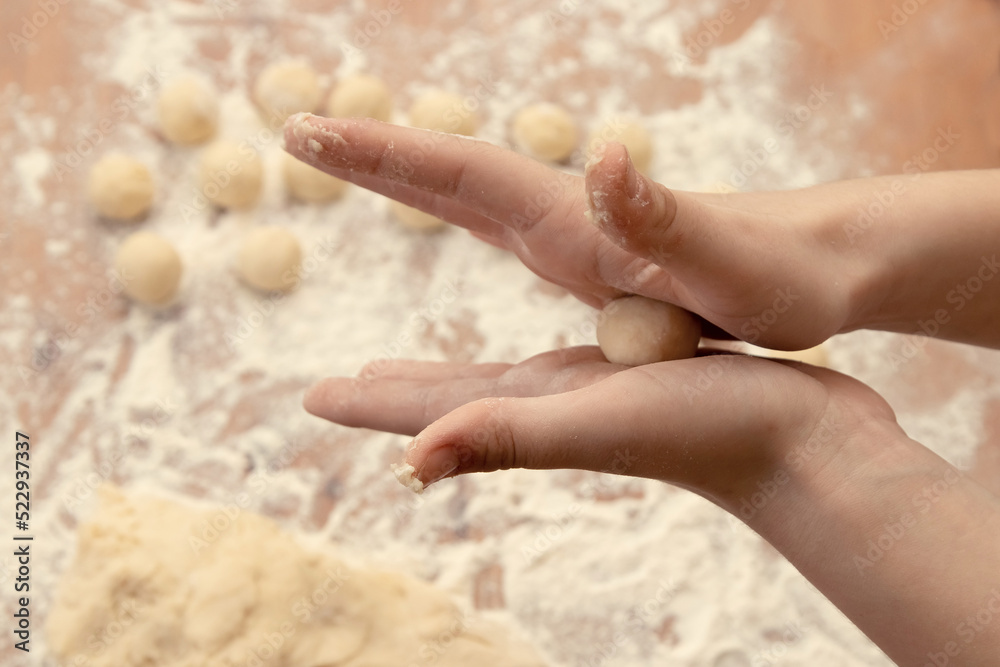 Children's hands roll a ball of dough between their palms against the ...