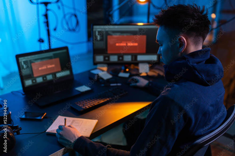cybercrime, hacking and technology concept - male hacker in dark room ...