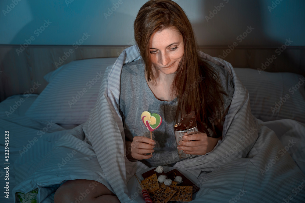 Woman late-night snacking in bed at home waking up hungry at night ...