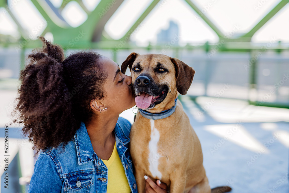 Multiracial girl sitting and resting with her dog outside in the bridge ...
