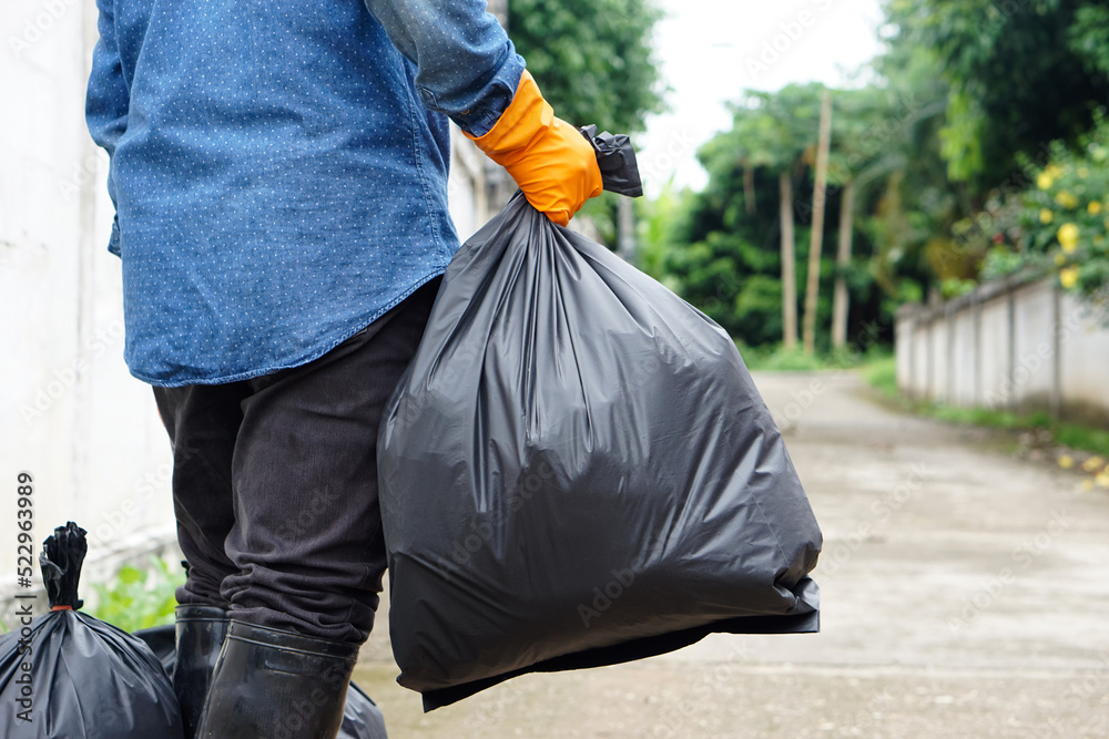 Closeup man holds black plastic bag that contains garbage inside ...